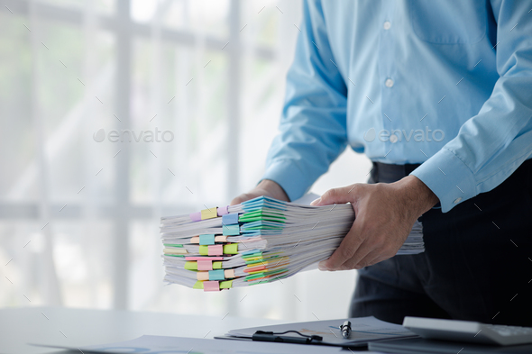 A person in an office with a huge stack of papers, he is a company ...