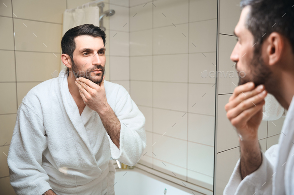 Handsome middle-aged man stands in front of mirror in bathroom Stock ...