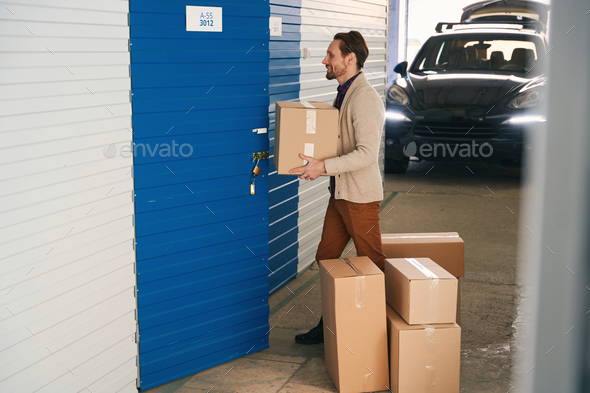 Side view of man with big cardboard boxes in self storage unit Stock ...