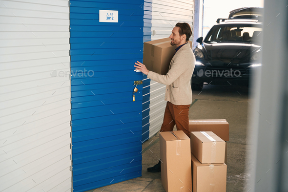 Side view of guy with big cardboard boxes in self storage unit Stock ...