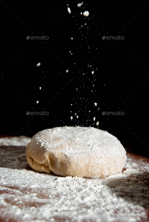 Vertical shot of throwing flour to the pizza dough Stock Photo by wirestock