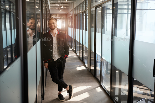 Smiling man facing camera in hallway of office Stock Photo by Iakobchuk