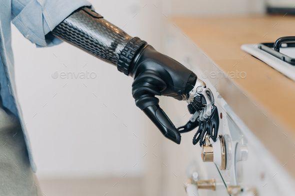 Electronic cyber hand of disabled person is switching a stove. Sensor ...