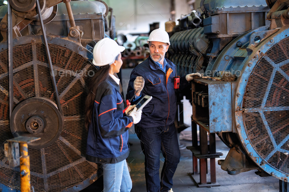 Workers and supervisor working in a maintenance shop checking heavy ...