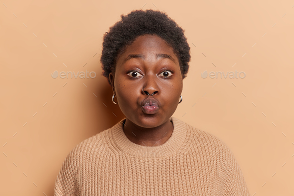 Portrait of dark skinned plump woman keeps lips rounded has surprised ...
