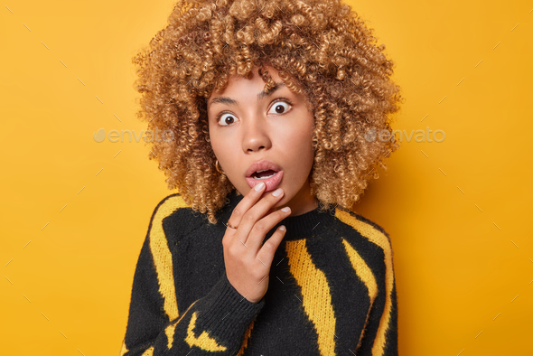 Photo of impressed stunned curly haired young European woman keeps hand ...
