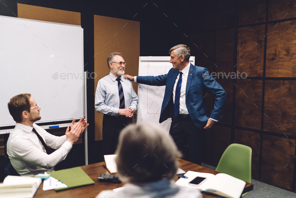 Optimistic partners celebrating success of colleague Stock Photo by ...