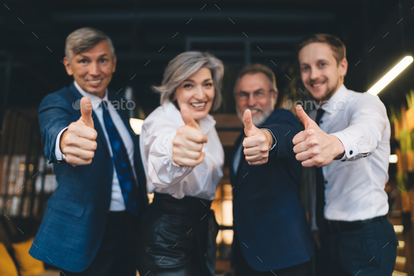 Positive group of colleagues standing with thumbs up in workspace Stock ...