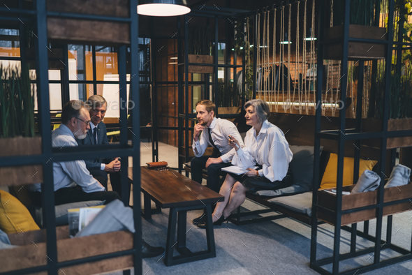 Colleagues discussing business plan in office lounge zone on couch ...