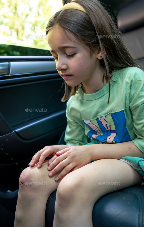 Close-up of little girl holding her bruised injured damaged knee with ...