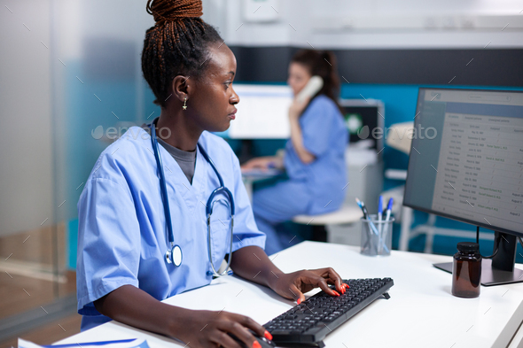 Nurse using computer at clinic desk Stock Photo by DC_Studio | PhotoDune