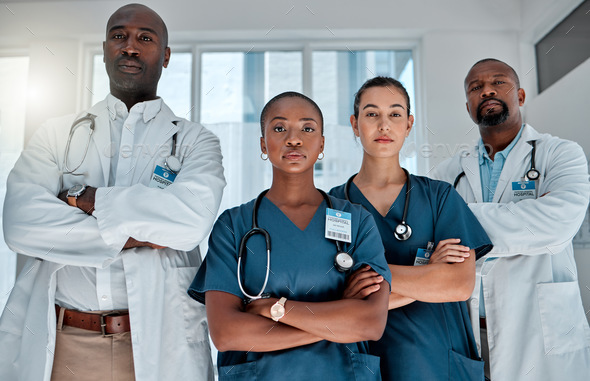 Group of serious doctors standing with their arms crossed while working ...