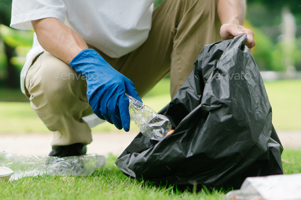 Man hand collecting plastic bottles into a black bag in a park.Ecology ...