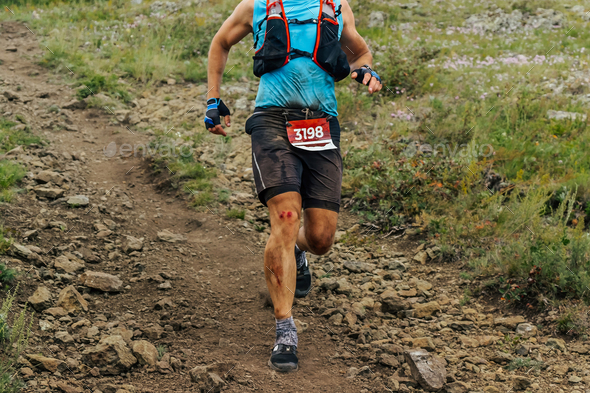 athlete runner running down mountain in trail marathon race, knee in ...