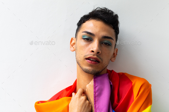 Portrait of biracial transgender man holding rainbow flag on white ...