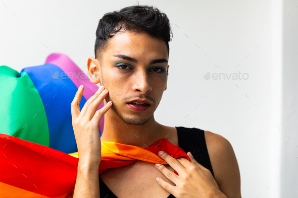 Portrait of biracial transgender man holding rainbow flag on white ...