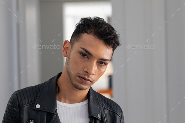 Portrait of biracial transgender man wearing biker jacket, looking at ...