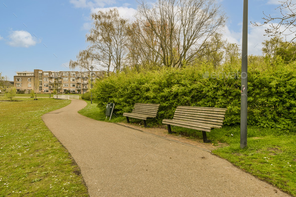 two park benches next to a path in a park Stock Photo by pro_creator
