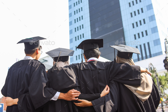 Backside view of graduate students hugging each other celebrating ...