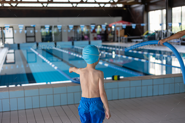 Boy swimmer from behind in blu swimming cap learning how to swim in a ...