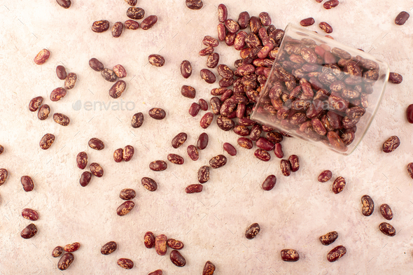 a top view brown raw beans inside and outside glass spread all over the ...