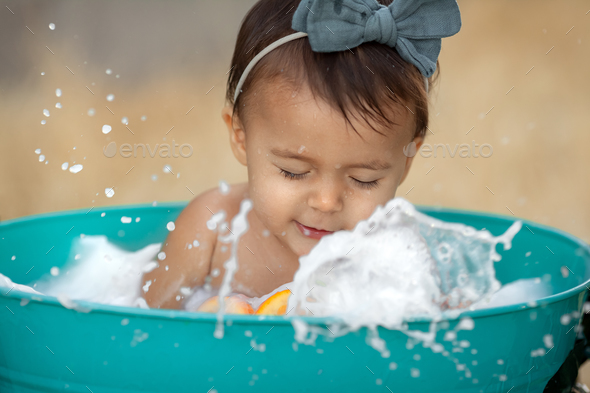 Baby girl bathing in a milk bath and splashing, babyhood and childhood ...
