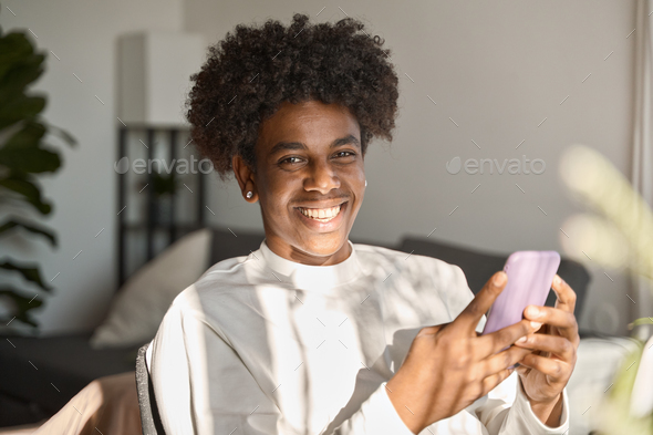 Happy gen z African American teen using mobile phone at home, portrait ...