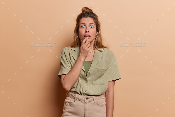 Horizontal shot of female model has shocked expression her eyes widened ...