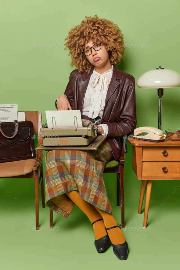 Sad tired curly haired woman works in vintage office setting poses on ...