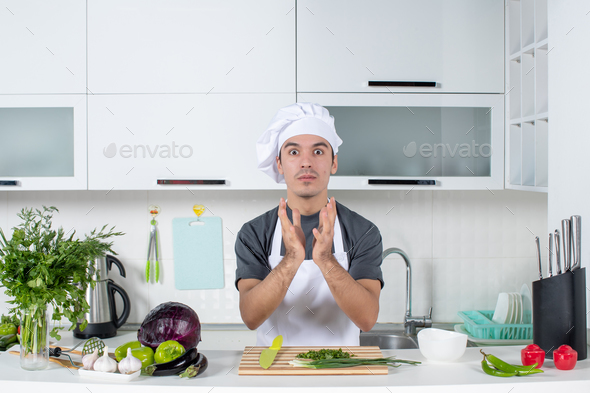 front view male chef in uniform clapping hands behind kitchen table ...