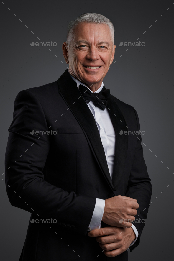 The distinguished old man stands confidently in a black suit Stock ...