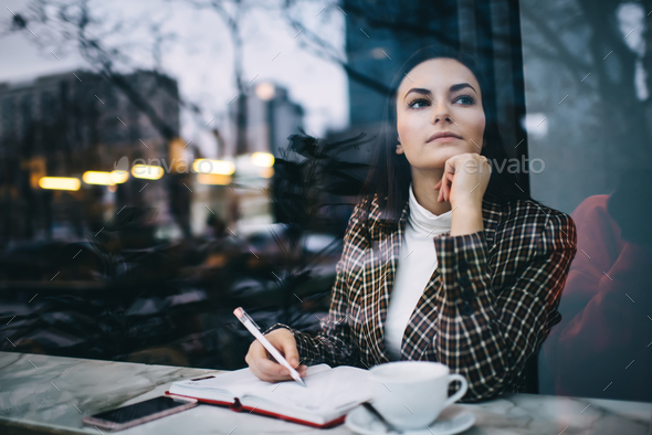 Wistful woman taking notes while working Stock Photo by GaudiLab ...