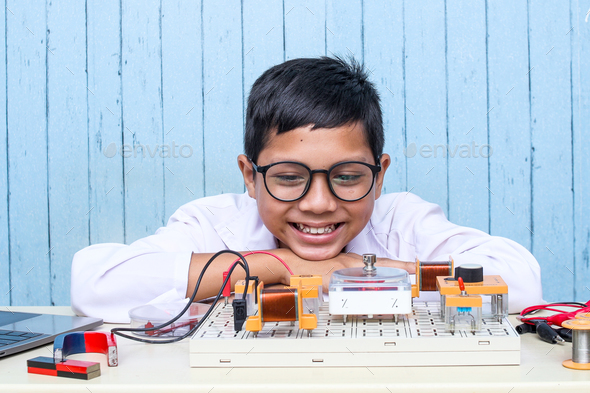 smiling Asian boy with circuits, wires, computer, motor. STEM education ...