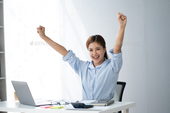 Cheerful young Asian business woman feeling overjoyed and celebrating ...