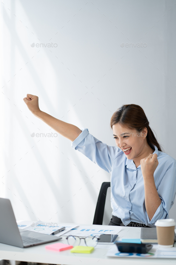 Cheerful young Asian business woman feeling overjoyed and celebrating ...