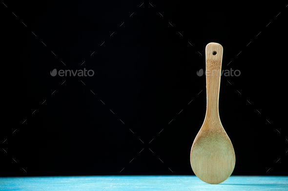 front view round wooden spoon placed upright on black background with ...