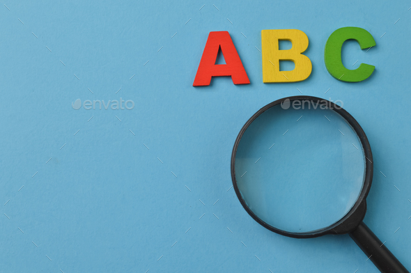 Magnifying glass and ABC letters isolated on a blue background with ...