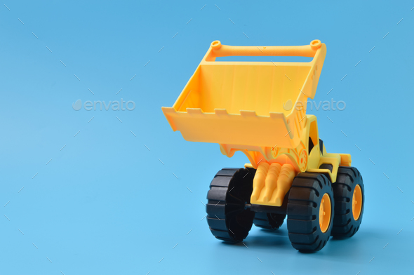 Construction plastic backhoe tractor toy isolated on a blue background ...