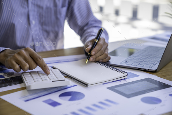 business office worker sitting at a desk using a calculator to ...