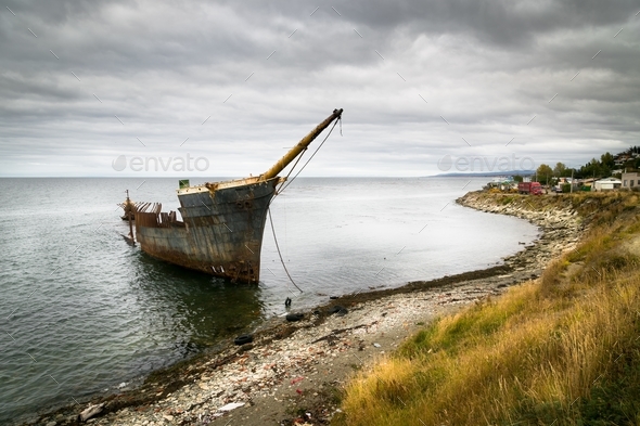 Broken ship parked on the shore with a cloudy sky Stock Photo by wirestock