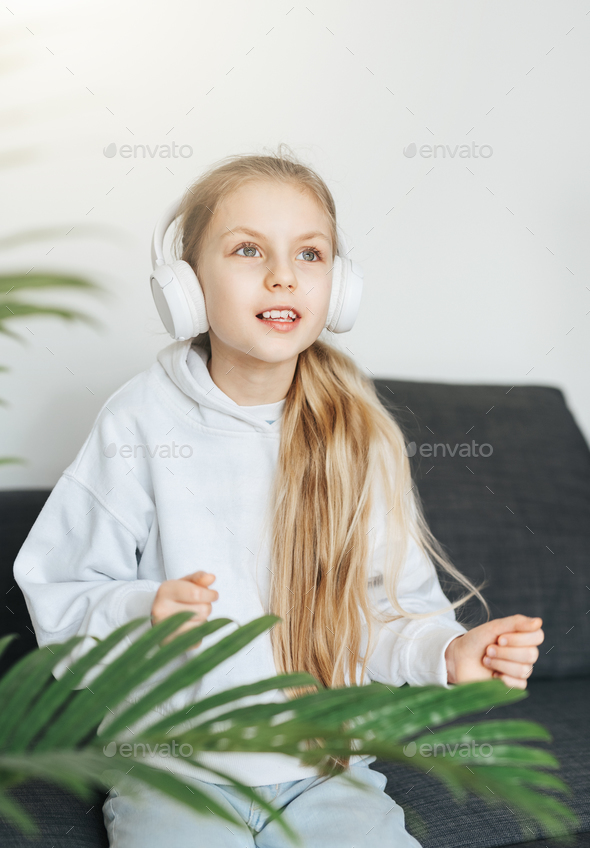 Cute little girl listening to music in headphones Stock Photo by Olena_Rudo