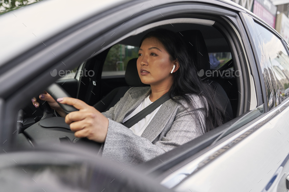 Chinese woman using earphones while driving a car Stock Photo by ...