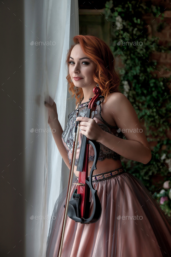 Cover woman violinist in art dress standing with violin near window ...