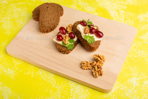 front view bread toasts with cheese and walnuts on the yellow ...