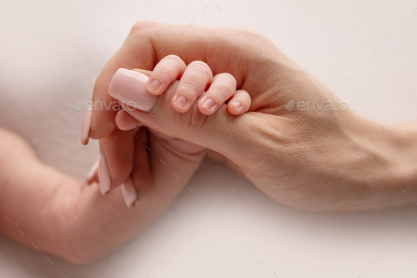 Close-up of a baby's small hand with tiny fingers and arm of mother ...
