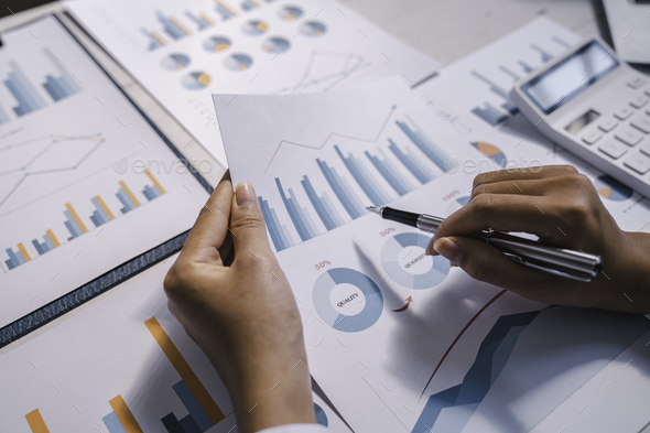 Businesswoman hold graph pens and use a calculator for the company's ...