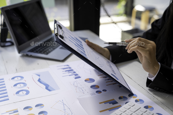 Businesswoman hold graph pens and use a calculator for the company's ...