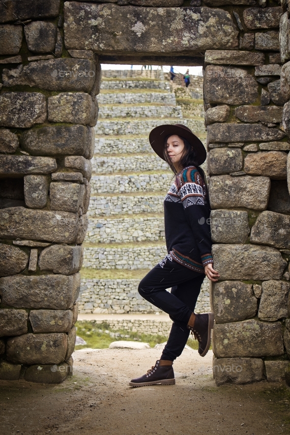 Vertical shot of a pretty girl posing at the lost old Inca city Machu ...