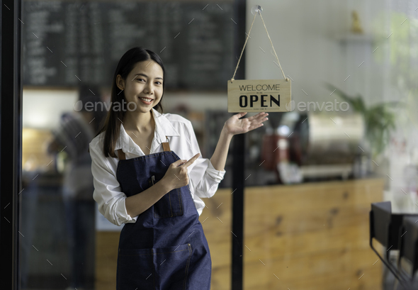 Happy waitress stands at the entrance of the restaurant showing off a ...