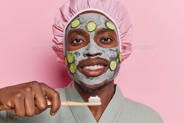 Horizontal shot of adult man applying mask with cucumber slices on his ...
